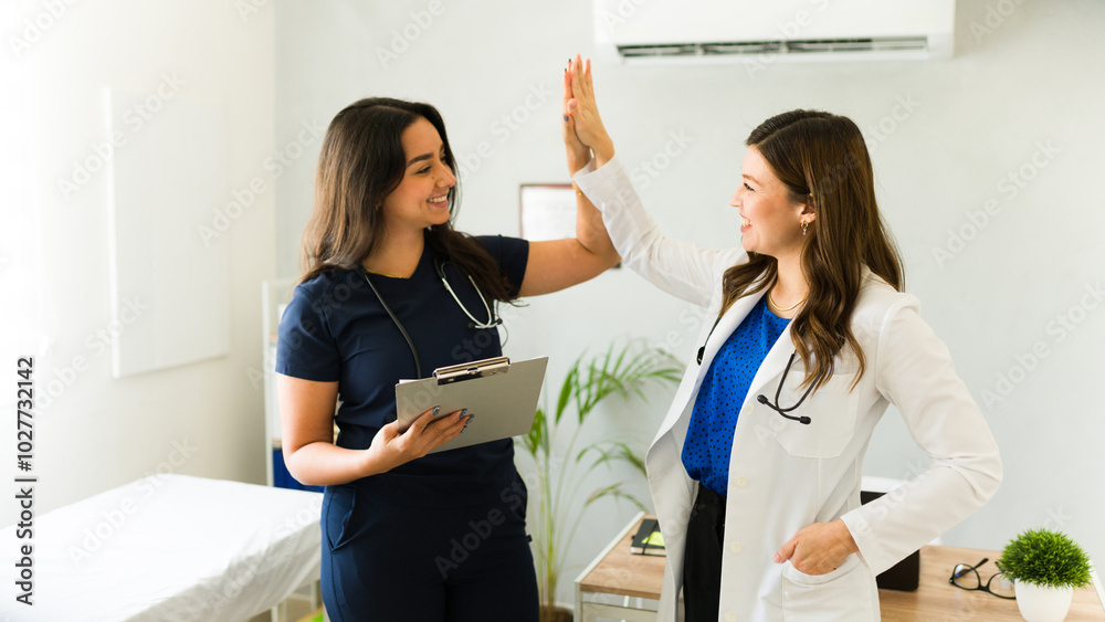 Two female doctors celebrating good news about patient treatment with a ...