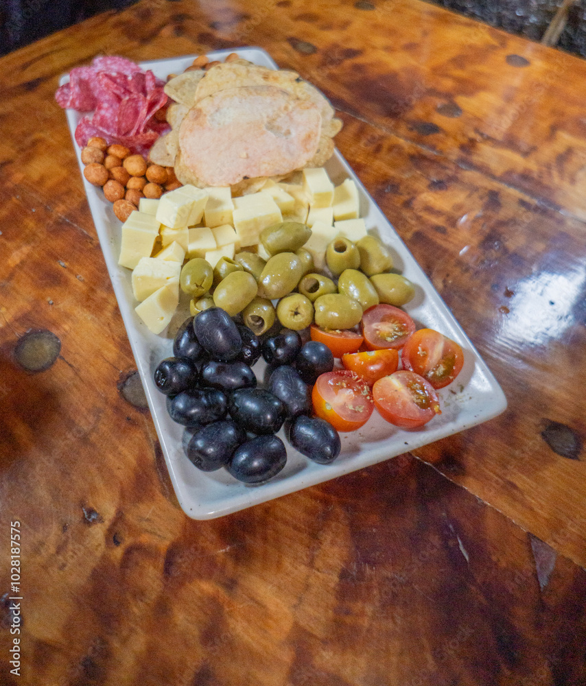 Tabla de cóctel con aceitunas, maní, jamón, tomate cherry, papas fritas ...