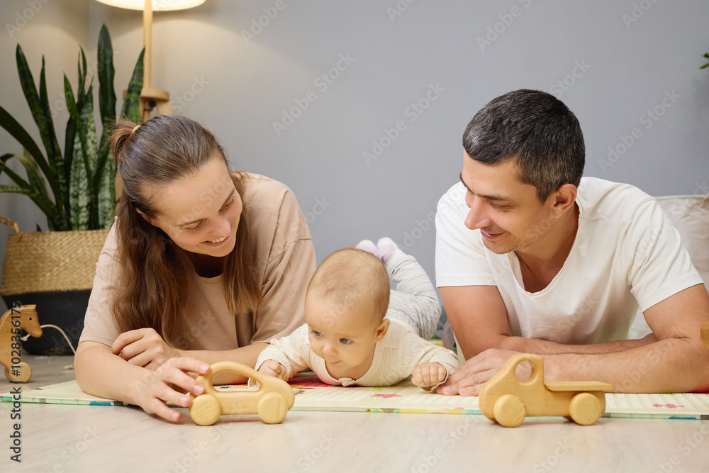 Mother and father playing with child engaged in floor play with baby in ...