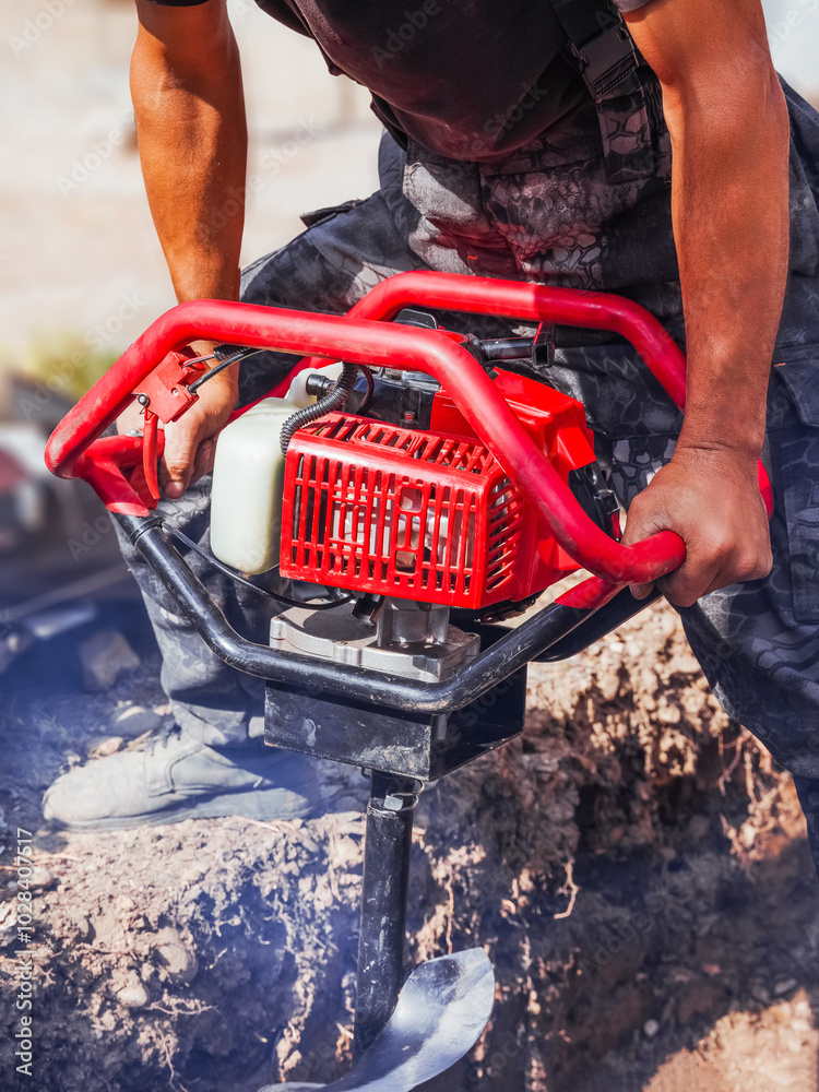 Drilling holes in the ground with a power drill. building a fence ...