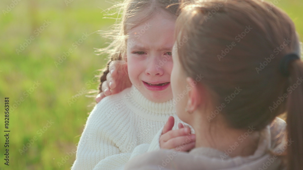 Foto de Child is crying in park in arms of mom. Mommy soothes baby ...