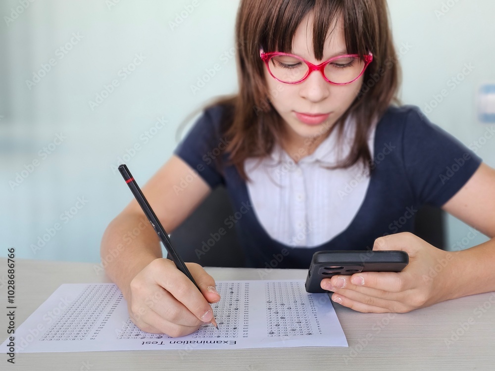 Student child holding smartphone during control exam test at school and ...