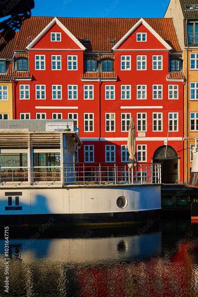 Red building in Nyhavn canal reflecting on water. Scandinavian ...