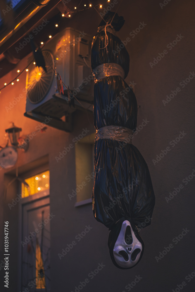 As a Halloween decoration, a masked corpse is hung in a bag, suspended ...
