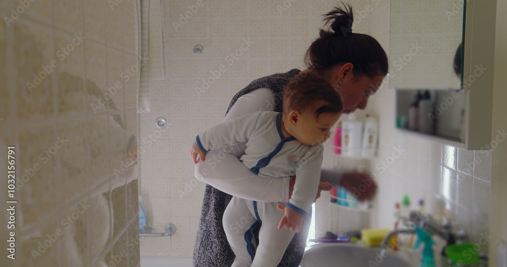 Mother multitasking as she brushes her teeth while carrying her baby in ...