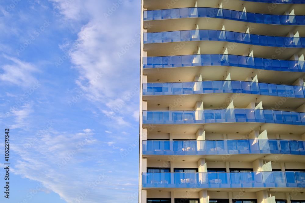 Modern high-rise building with balconies and blue sky. Perfect for real ...
