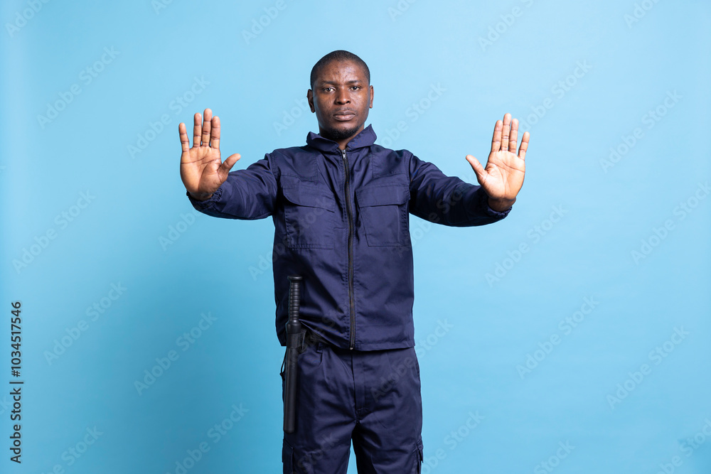 Security guard putting his hands up as a stop sign in studio, creating ...