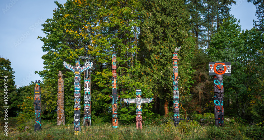 Colourful totem poles stand proudly in a lush forest, representing the ...
