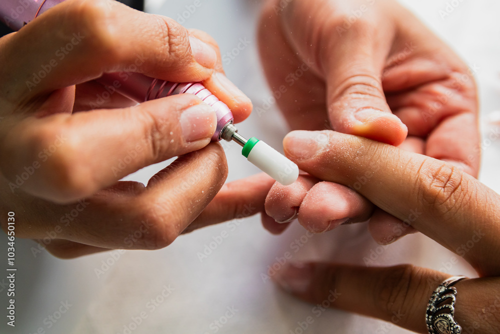 Close-up of a nail technician giving a manicure using an electric nail ...