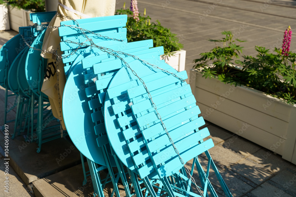 Colorful blue tables secured with chains outside a bustling cafe in the ...