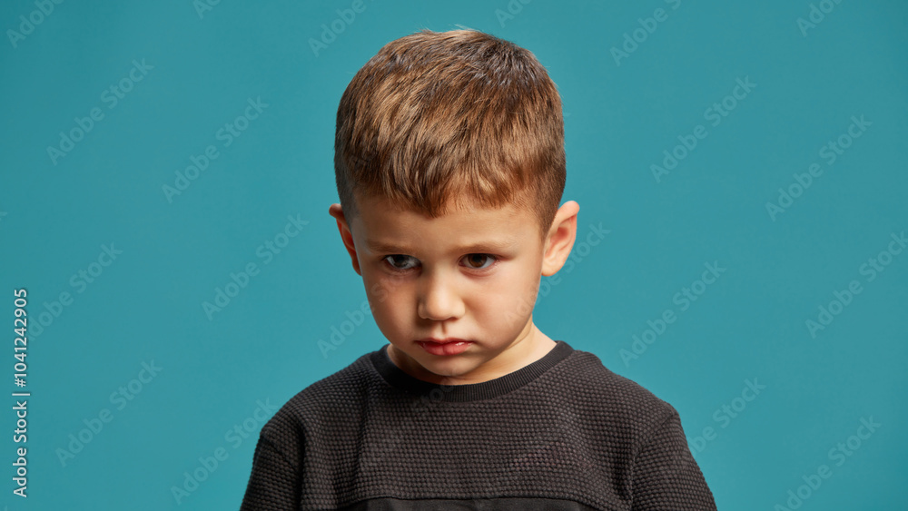 Little boy stares intently with a serious, determined expression ...