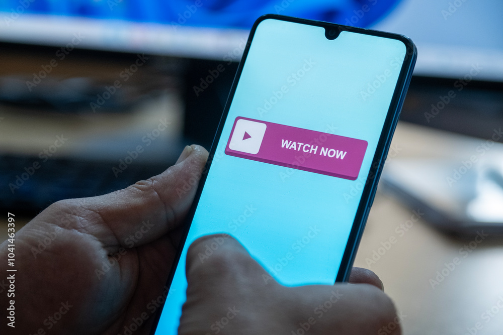 “Watch Now” message on close-up smartphone screen. Watching online ...