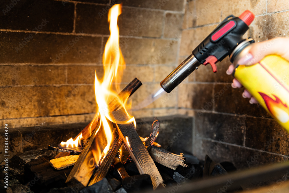 This image shows a fireplace being lit using a butane torch. The flame ...