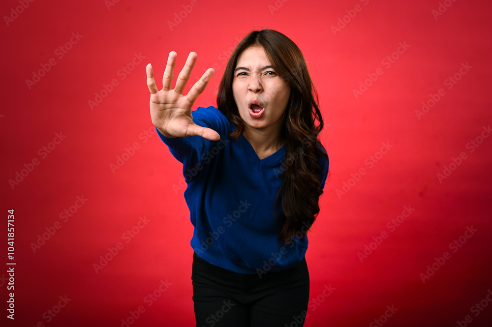 An Asian woman in a blue sweater is making a "stop" gesture with her ...