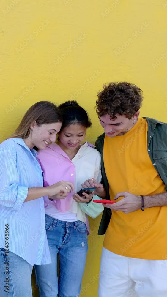 Three multiracial college students using mobile phones standing ...