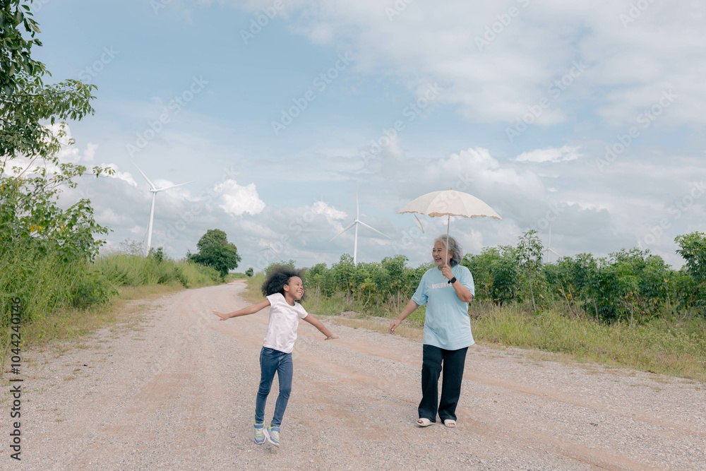 Grandma holds an umbrella and takes her granddaughter for a relaxing ...