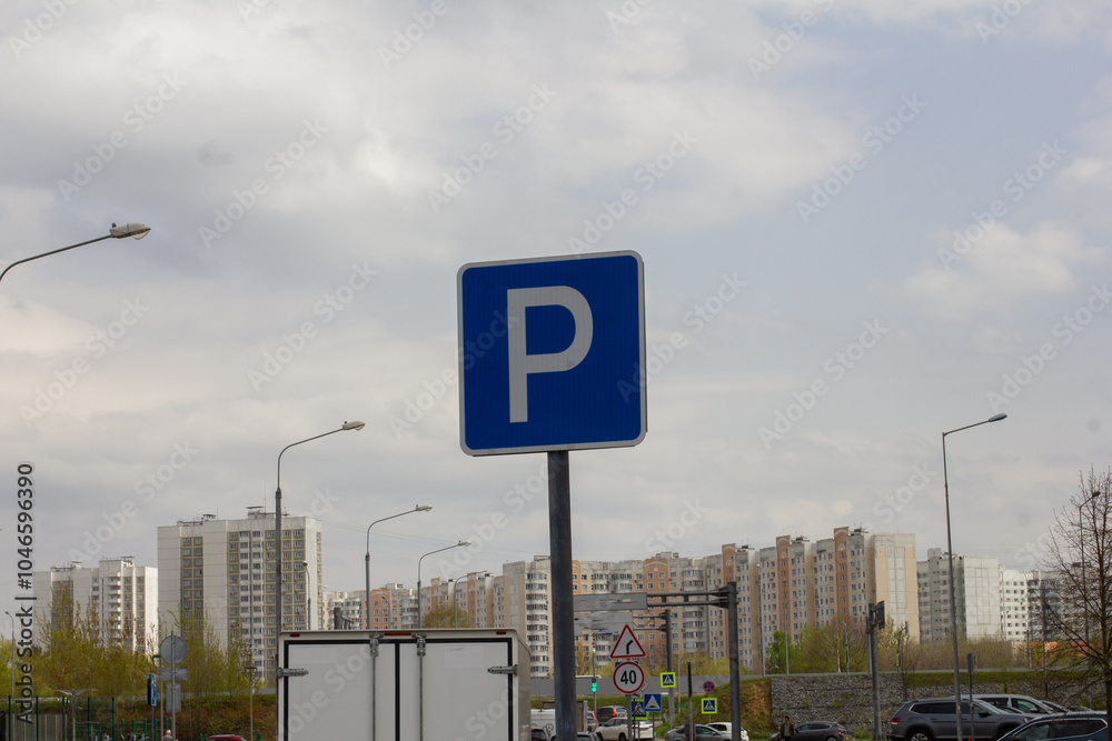 A blue parking sign stands against a backdrop of residential buildings ...
