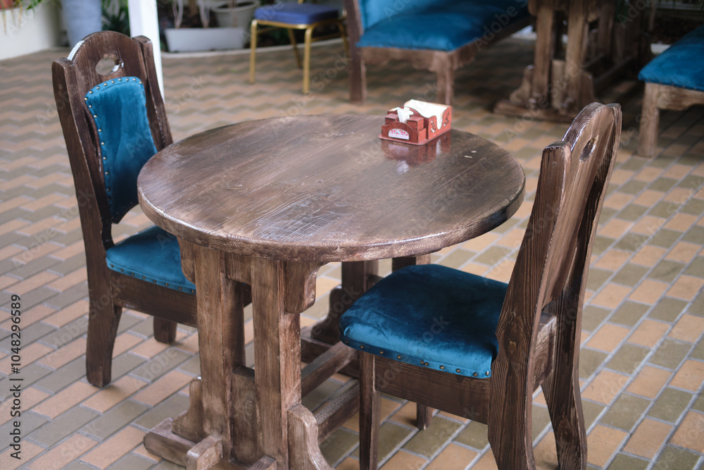 Rustic wooden table with two chairs featuring blue velvet cushions in a ...