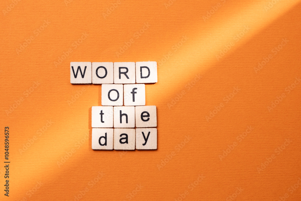 Word of the Day written with square wooden letter tiles on orange ...