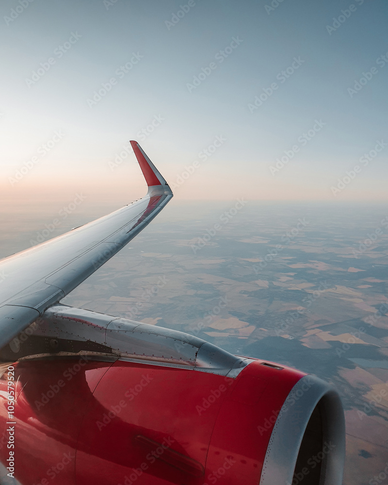 Flying above countryside at sunrise - window seat view. Aircraft red ...