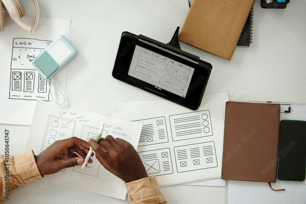 Hands sketching wireframes on paper with tablet displaying digital ...