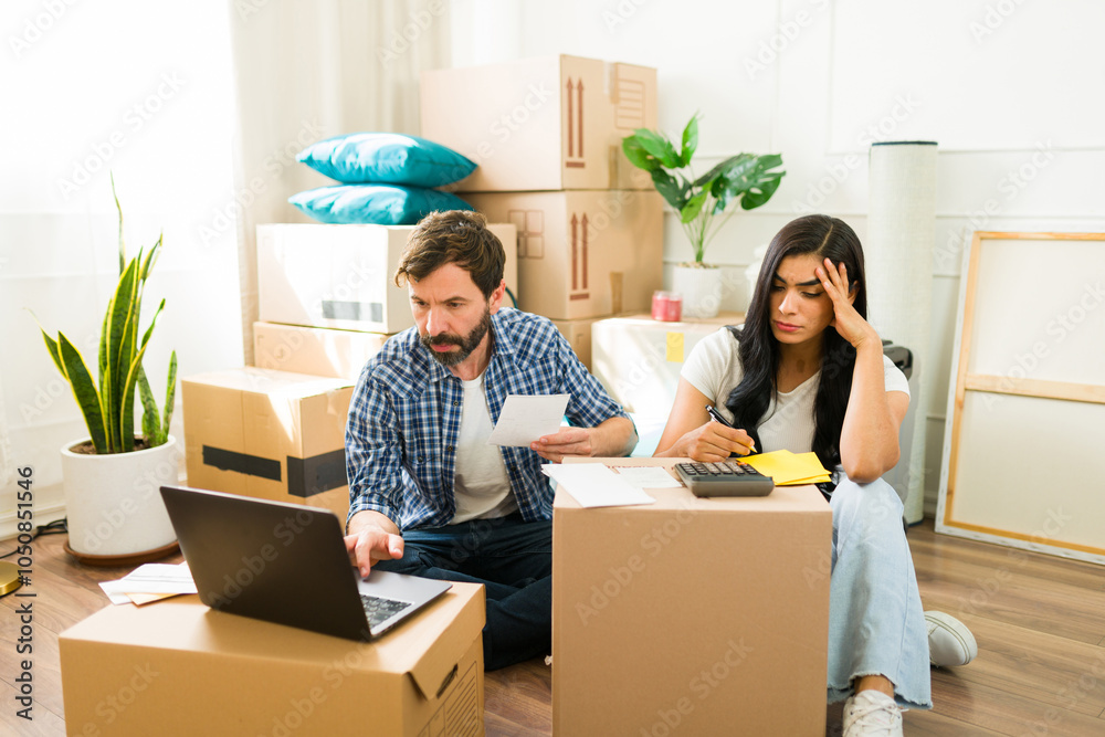 Overwhelmed young couple surrounded by cardboard boxes while ...