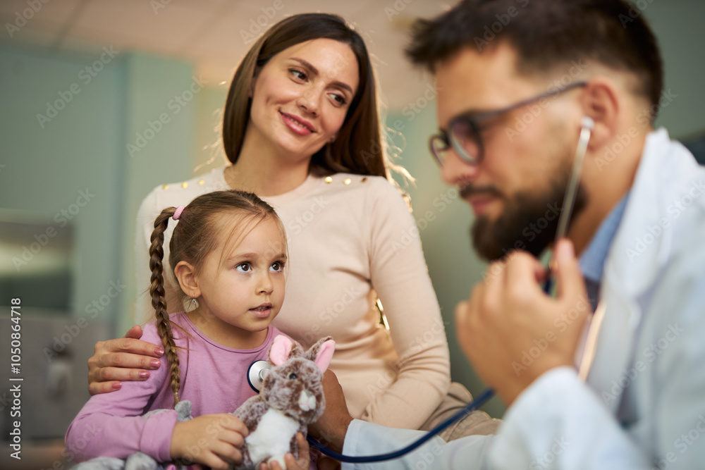 Cute girl having a medical exam with her mother at pediatricians ...