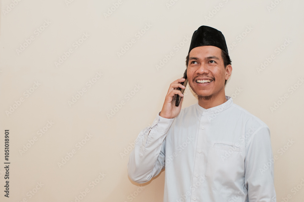 Smiling Southeast asian muslim man using smartphone taking a call and ...
