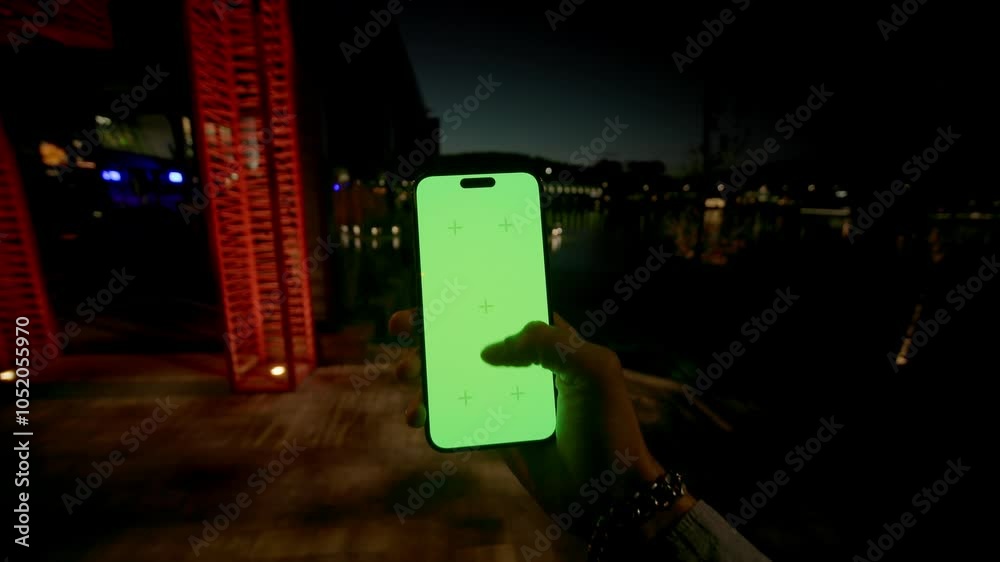 Male hand holding smartphone in vertical mode with green mock up screen ...