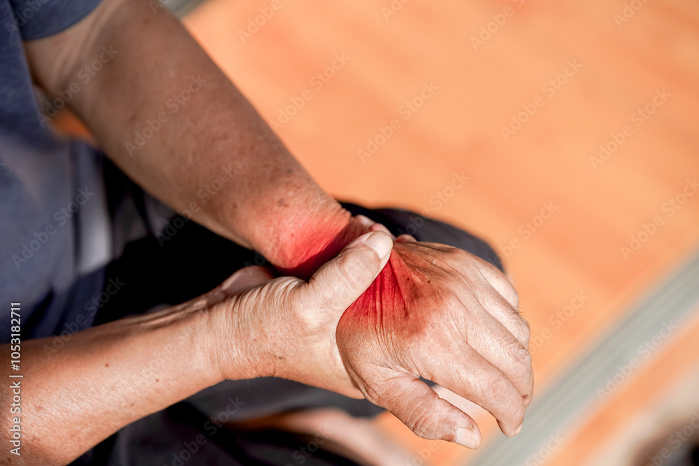 person is holding their wrist, showing signs of discomfort or pain ...