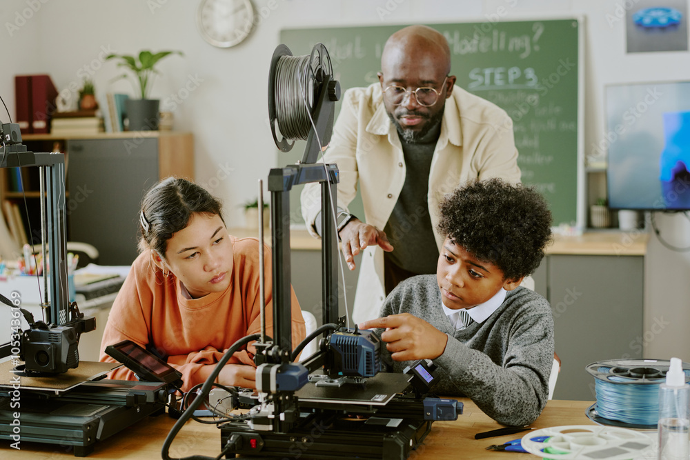 Teacher guiding two students in using 3D printing technology in ...