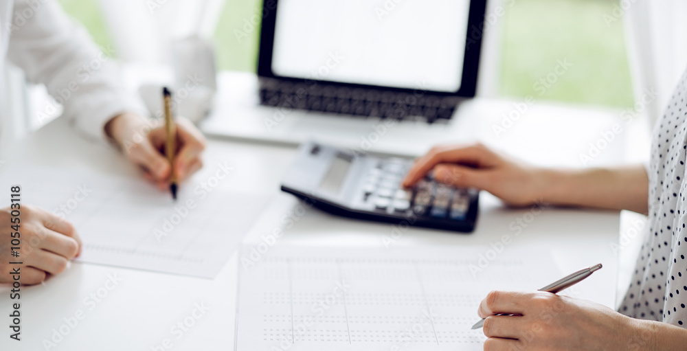 Two accountants using a calculator and laptop computer for counting ...