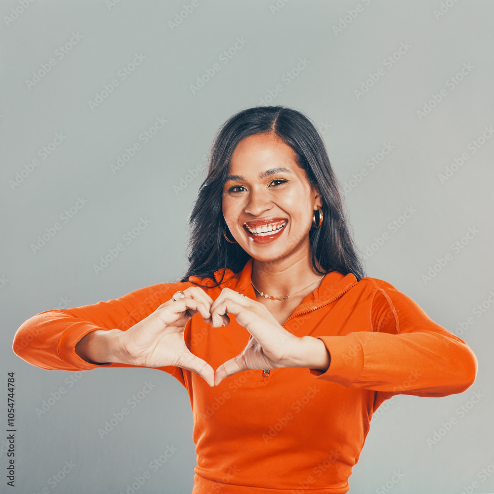 Heart hands, portrait and smile of woman in studio on gray background ...