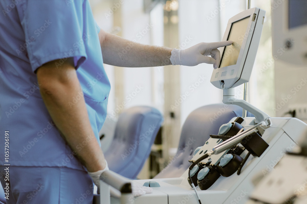 Medical professional in scrubs adjusting touchscreen on medical device ...