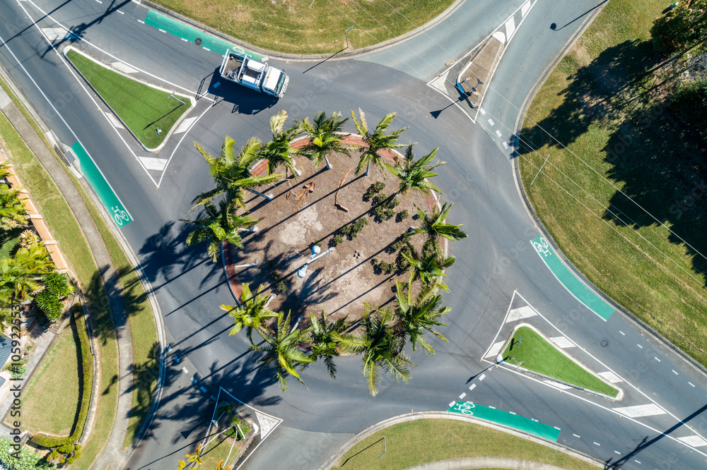 Aerial drone view of work ute entering a roundabout with palm trees in ...