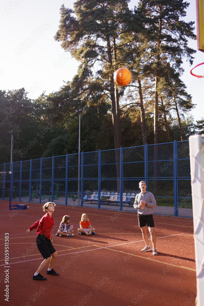 Student learning to throw basketball into basket supervised by trainer ...