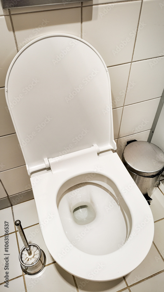 A clean, white toilet in a tiled bathroom highlights sanitation and ...