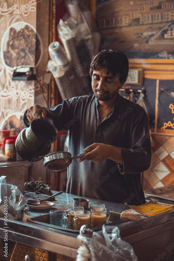 Pakistani street vendor pouring chai tea into cups in his roadside tea ...