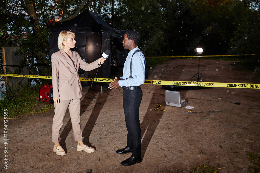 Full length portrait of female reporter interviewing police officer at ...
