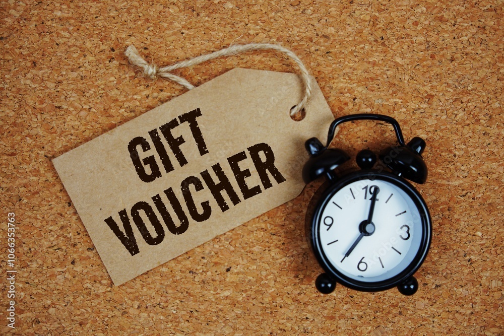 Gift Voucher text on price tag with alarm clock on cork board ...