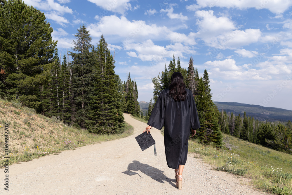 Teenage girl in high school graduation cap and gown walking away on a ...