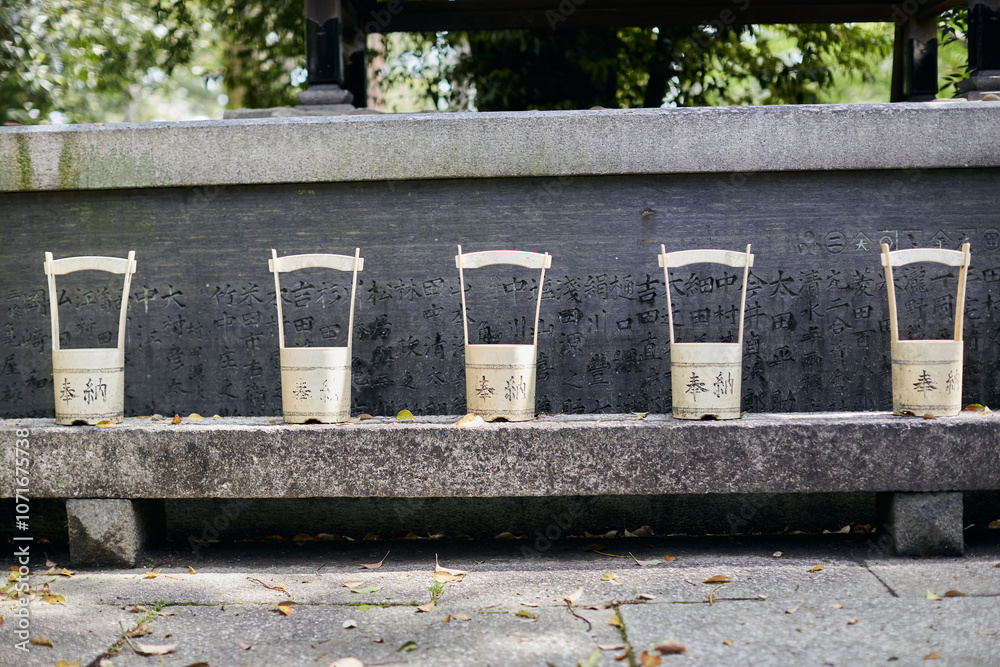 Row of traditional Japanese wooden buckets lined up on a stone platform ...