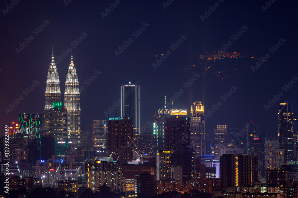 Kuala Lumpur's nightscape shines brightly with twinkling city lights against the distant and ...