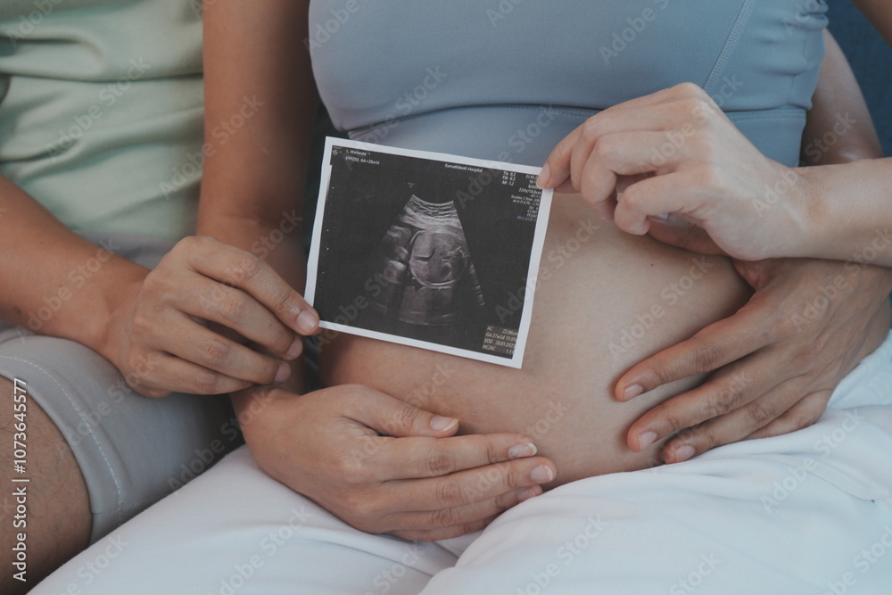 The hands of the pregnant parents hold the seven-month pregnant mother ...