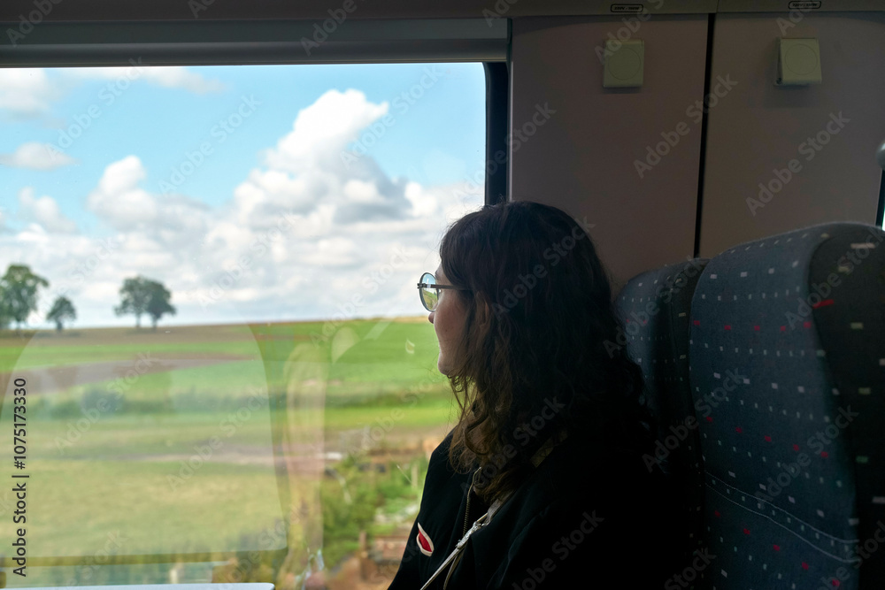 Passenger gazing out the window of a train observing the passing ...