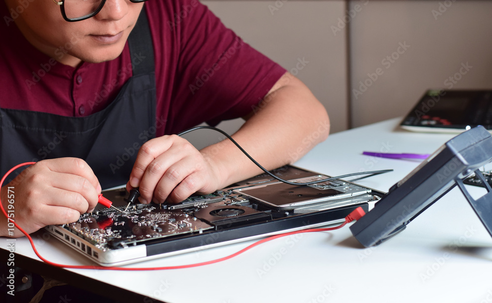Computer technician wearing glasses A laptop motherboard repairman is ...