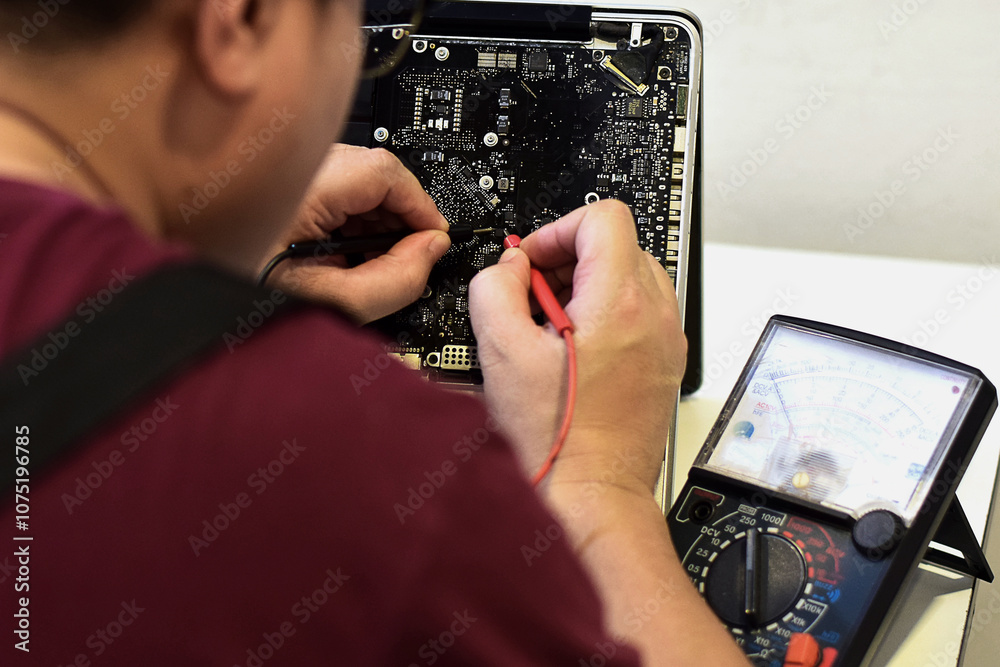 Computer technician wearing glasses A laptop motherboard repairman is ...