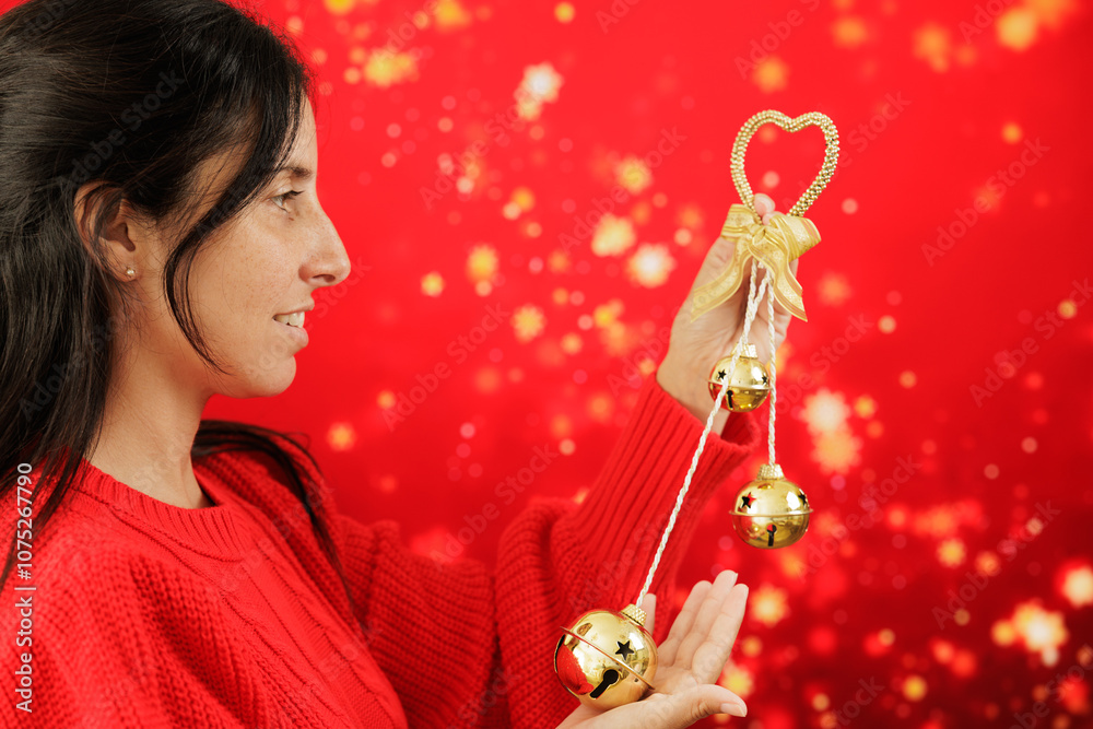 Young woman holds a golden heart-shaped Christmas object with jingle ...