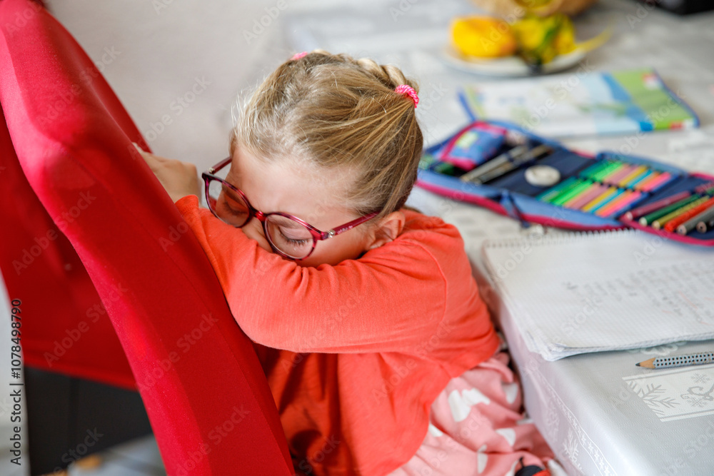 The little schoolgirl is upset and depressed, covering her face with ...