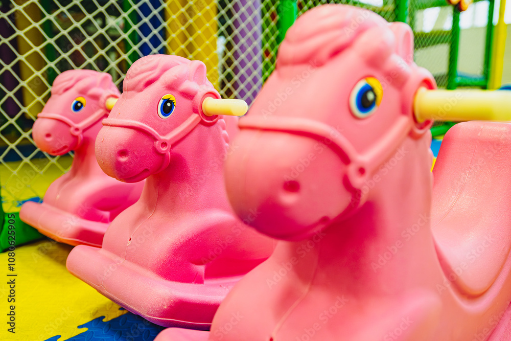 Three pink rocking horses sit in a vibrant indoor play area designed ...